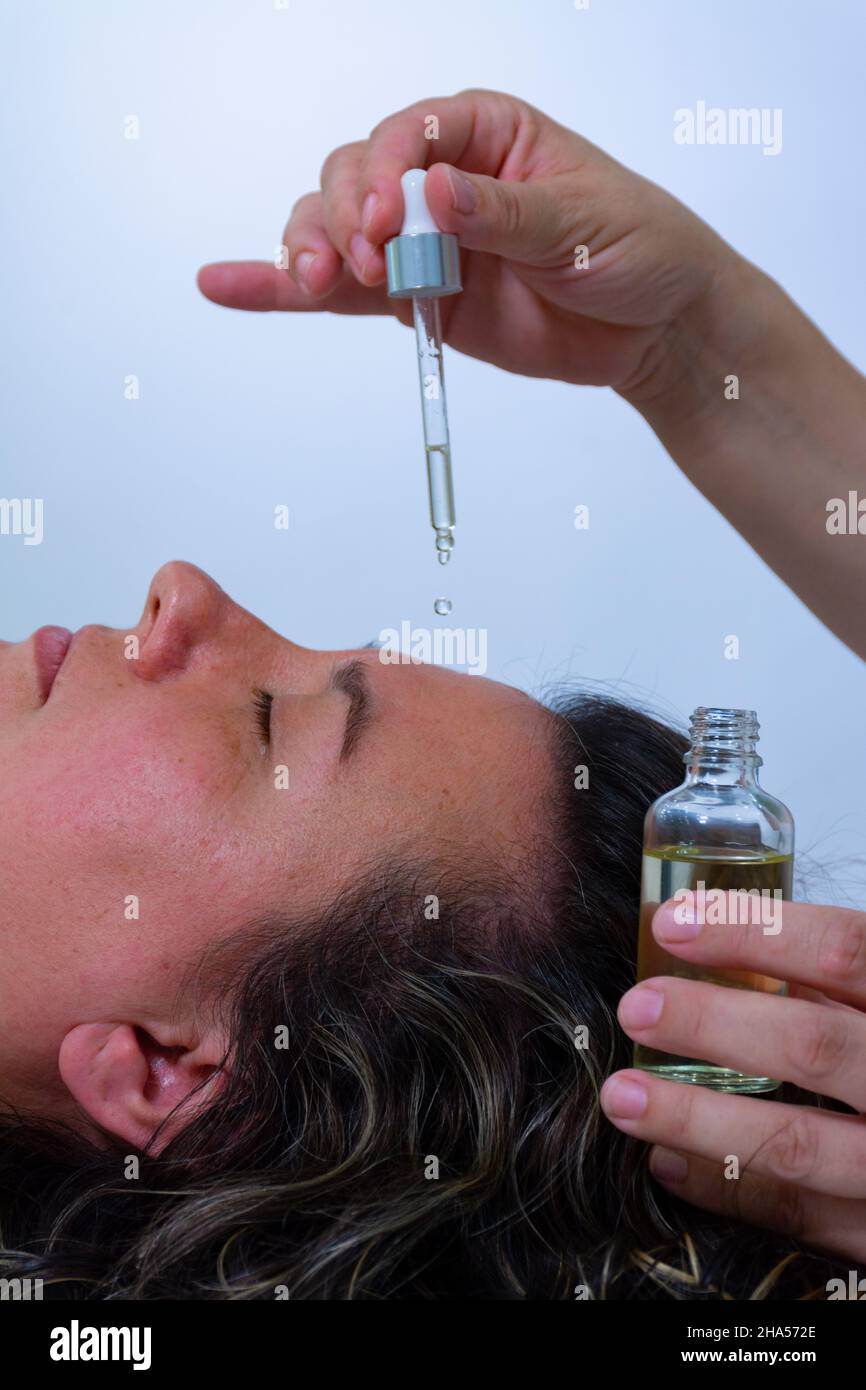 Drop of essential oil falling from a dropper of therapist onto the ...