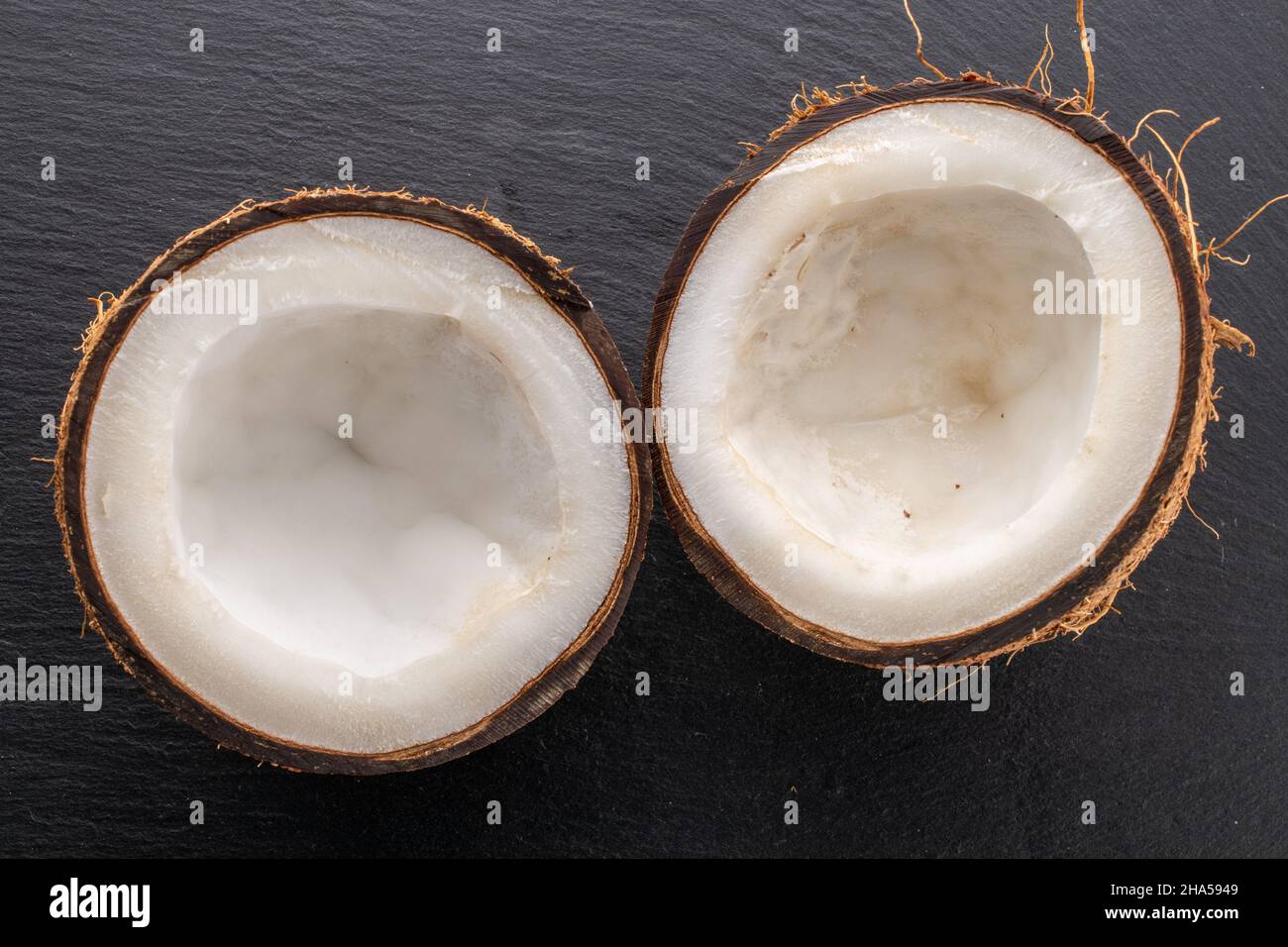 Two halves of fresh coconut, close-up, on a slate board, top view Stock ...