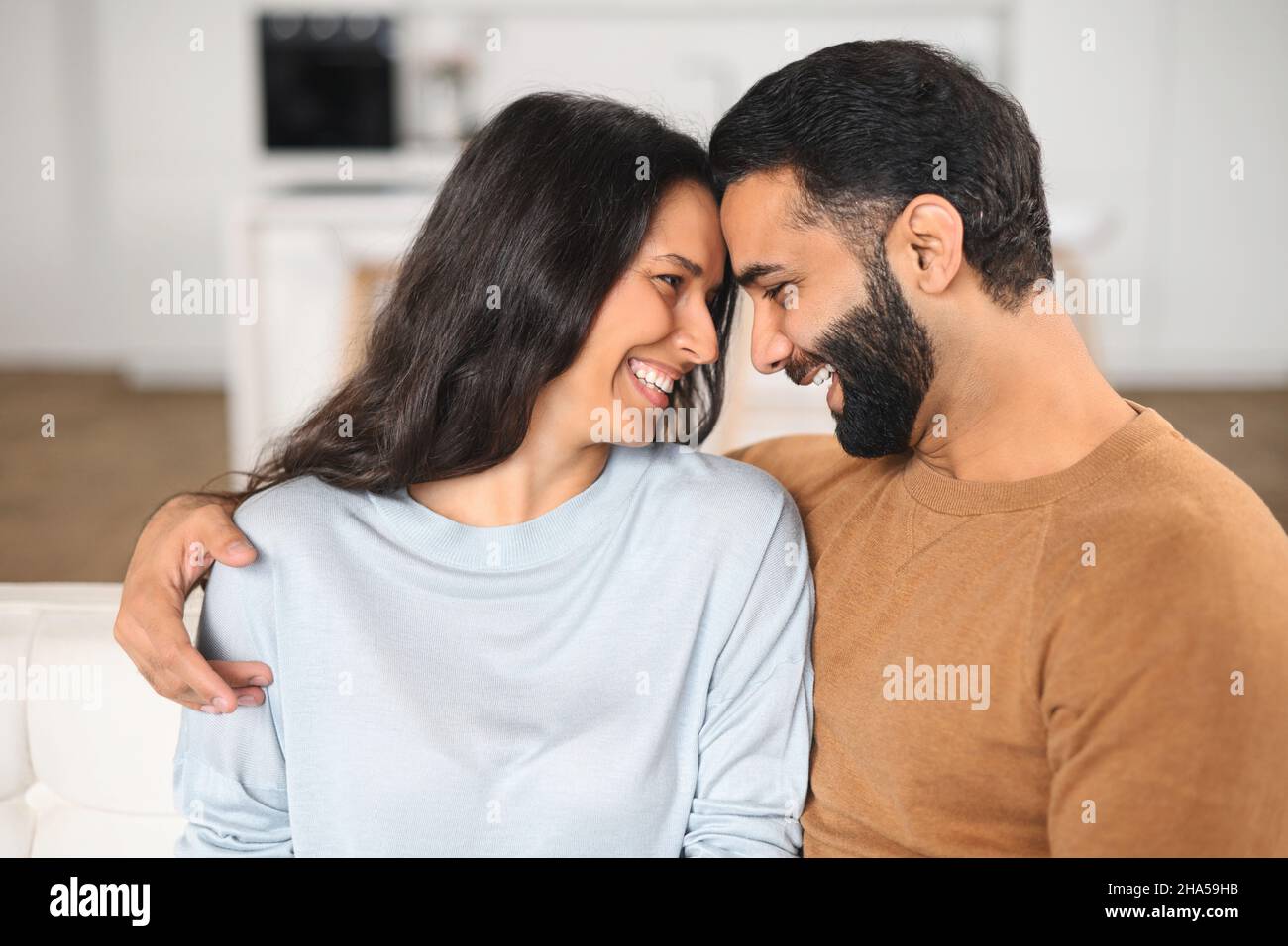 Carefree And Cute Couple In Love Sitting In Embrace On The Cozy Couch