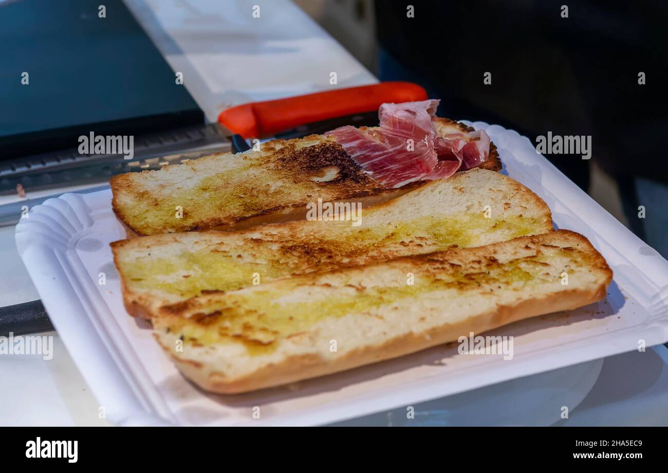 preparing toasts of Iberian ham and olive oil typical Spanish food ...