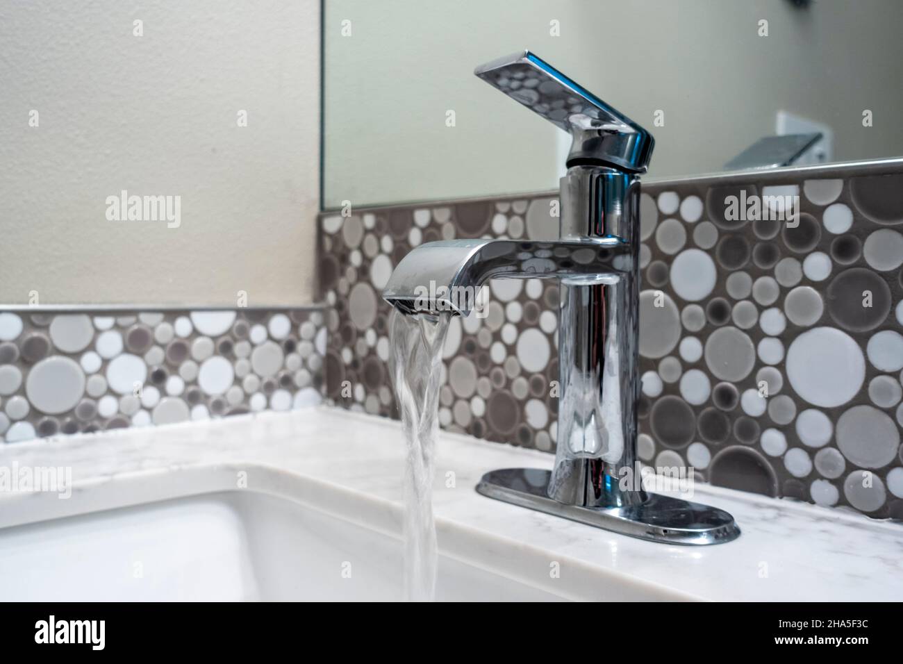 Close up view of a sink faucet inside an upscale bathroom, the water ...