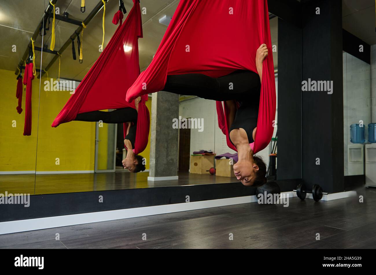 Young sporty African slim body woman practicing aerial flying yoga ...