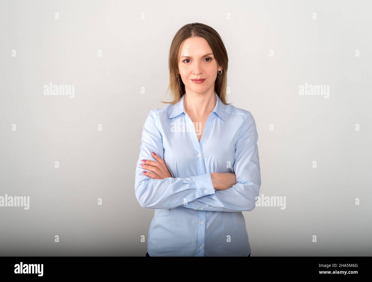 Portrait of young attractive business lady with folded arms over white ...