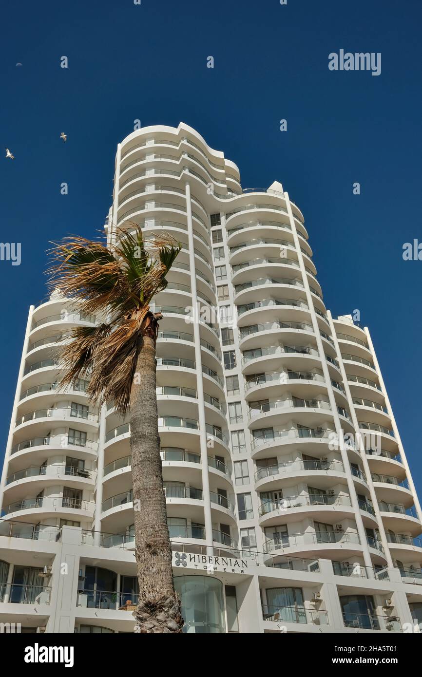White beach side building against a clear blue sky and a palm tree ...