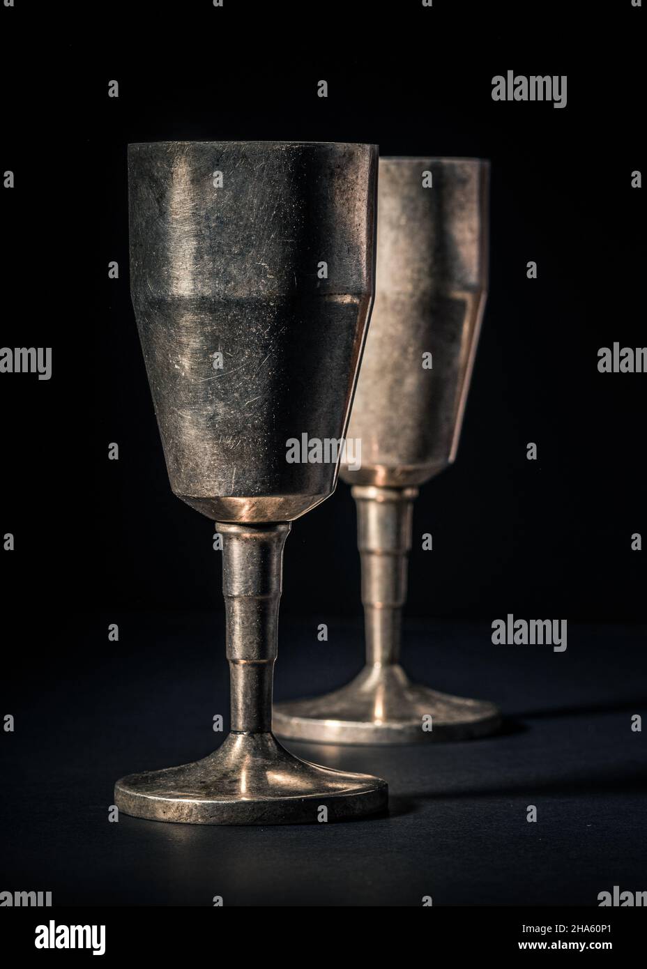 Vertical shot of antique silver glasses under light spot on a black ...