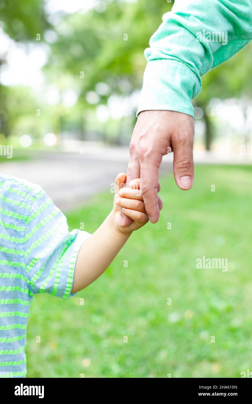 Father and toddler holding hands. Toddler gripping father's finger ...