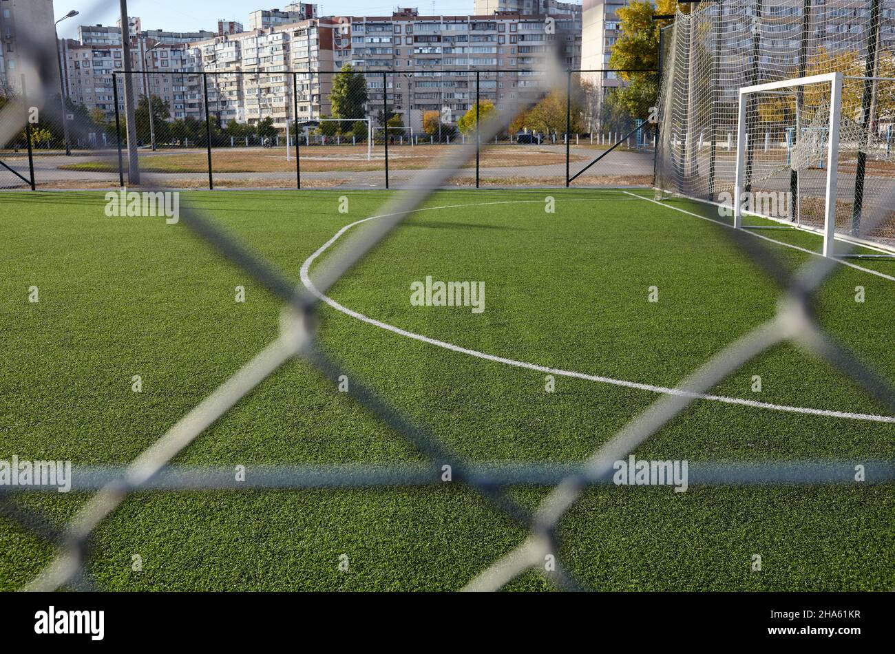 Lawn field for playing football behind the green fence mesh. Close-up ...