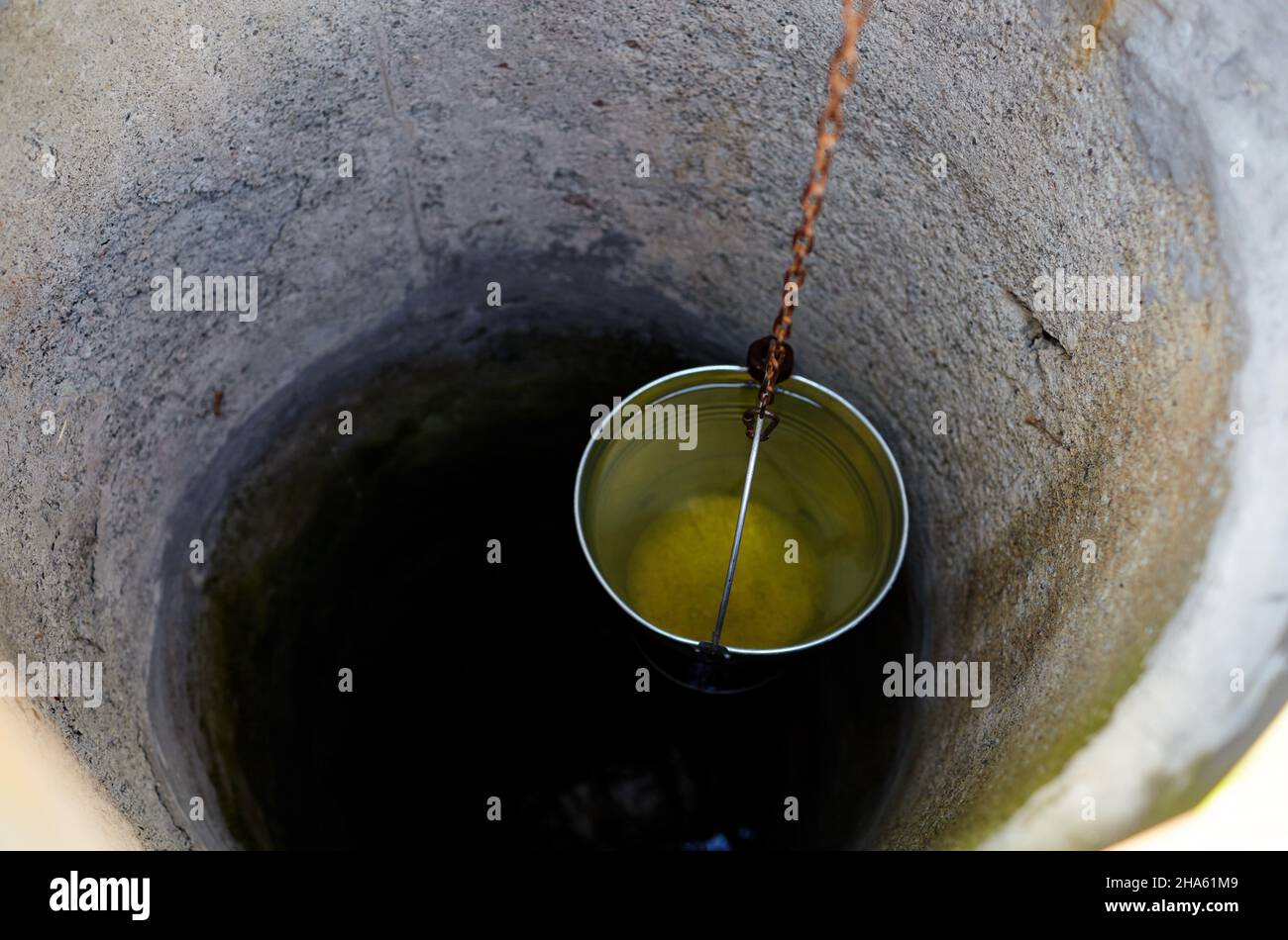 Metal bucket in draw-well in European village. Retro stone water well ...