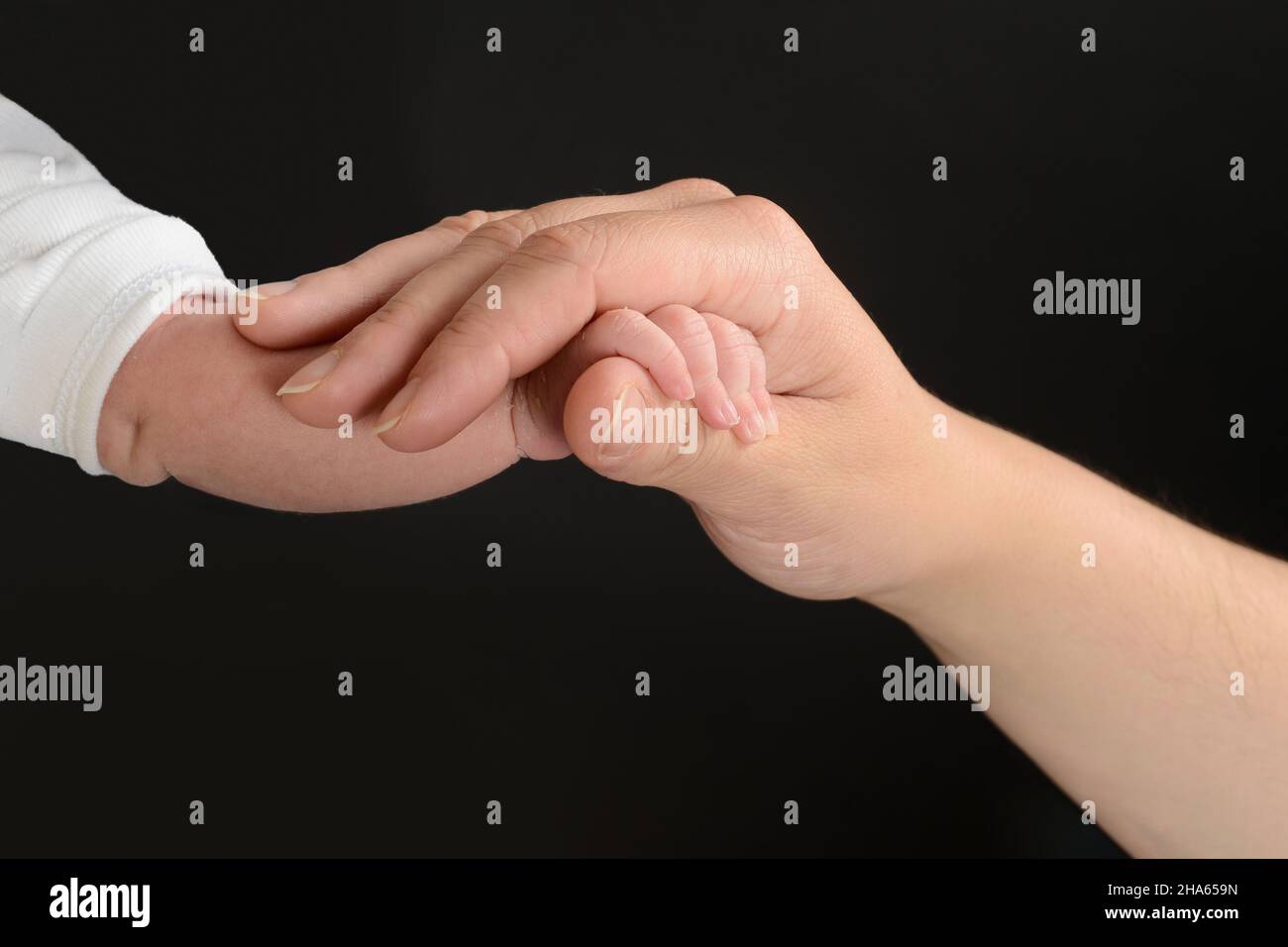 Small hand of a newborn baby held by the hand of its mother where the ...
