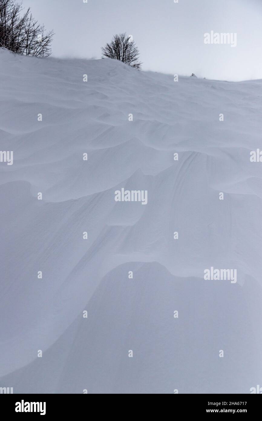Vertical shot of pistes on hills covered in the snow under a cloudy sky ...