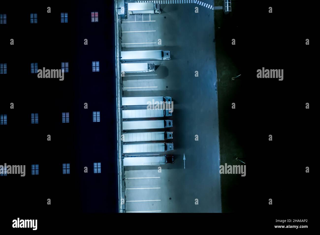 Night Modern logistics center, white van and trailers standingon ramp ...