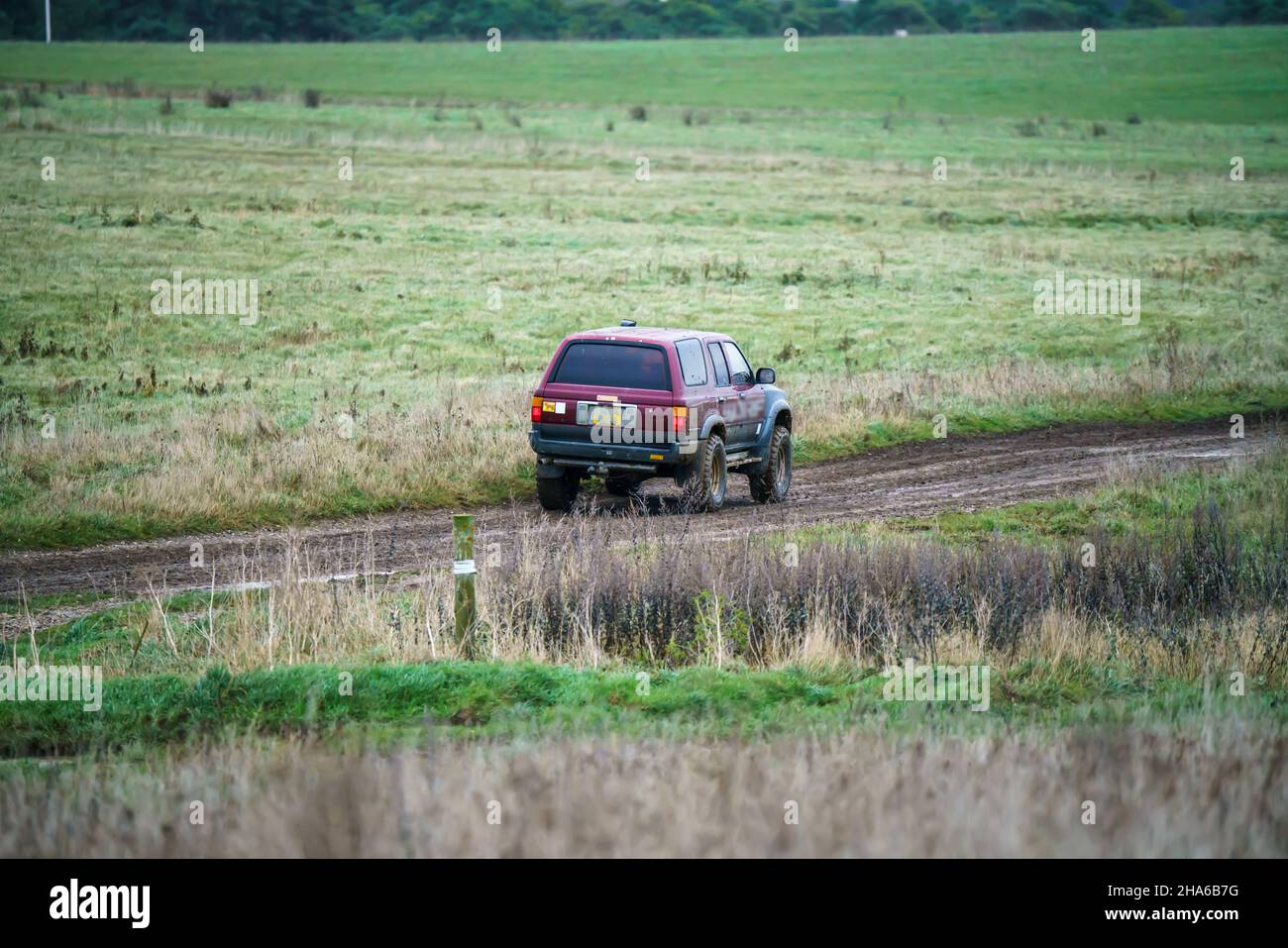 4x4 off-road vehicle driving across mud and water-logged terrain ...