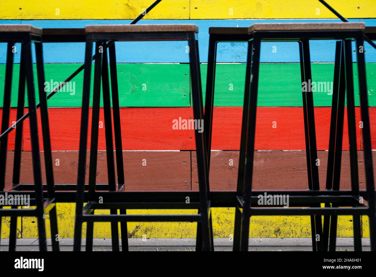 Stools in front of rainbow coloured wall, at an outdoor café in ...