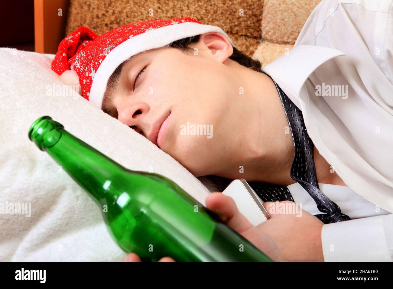 Teenager sleeping in Santa Hat and Bottle of the Beer on the Sofa Stock ...