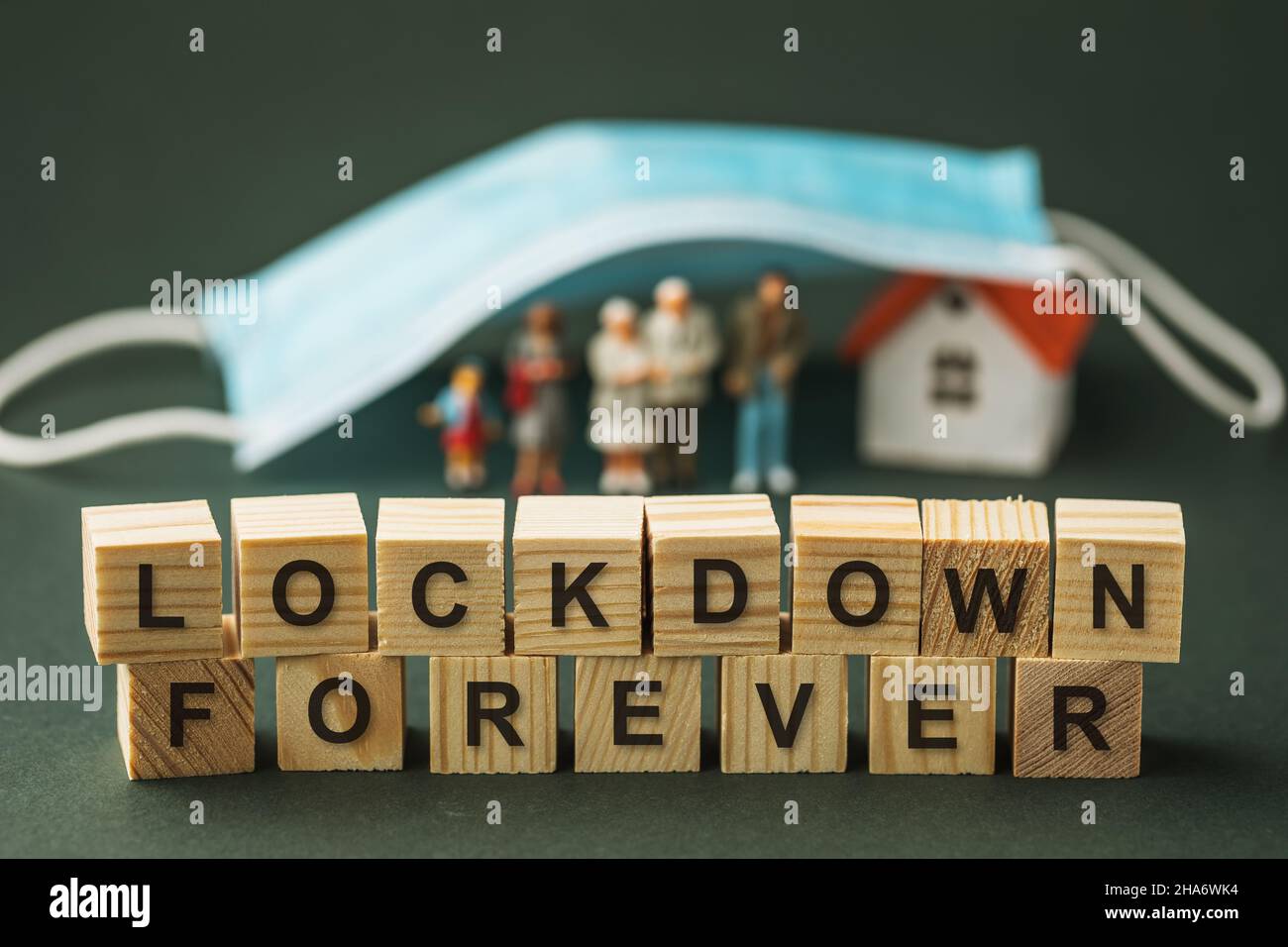 Medical mask, plastic toy men with a house and wooden cubes with text ...