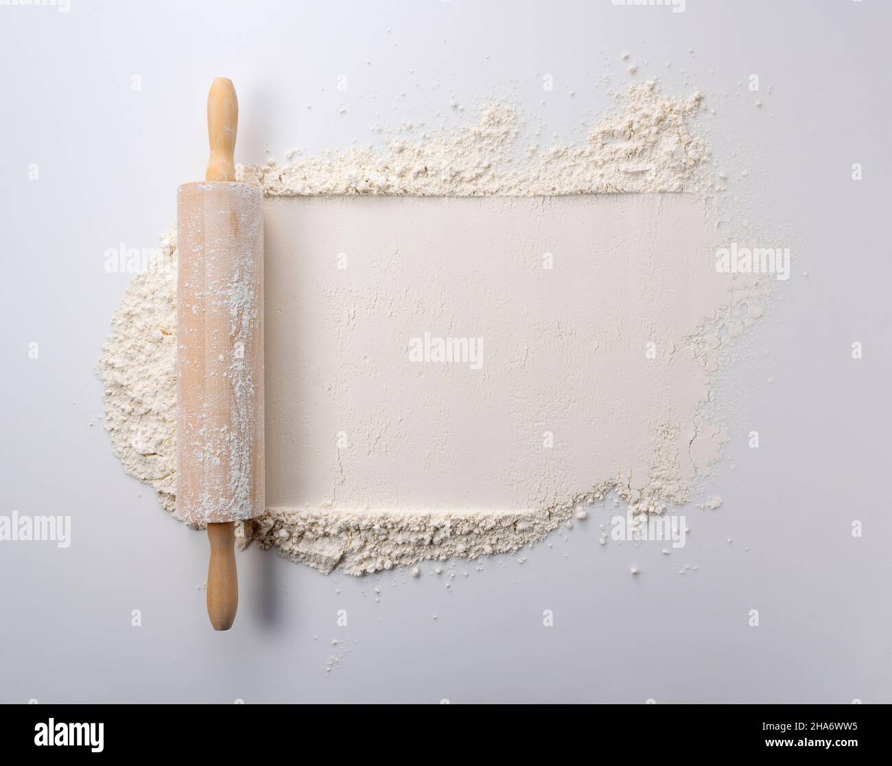 A rolling pin rolled over flour on a white background. View from ...