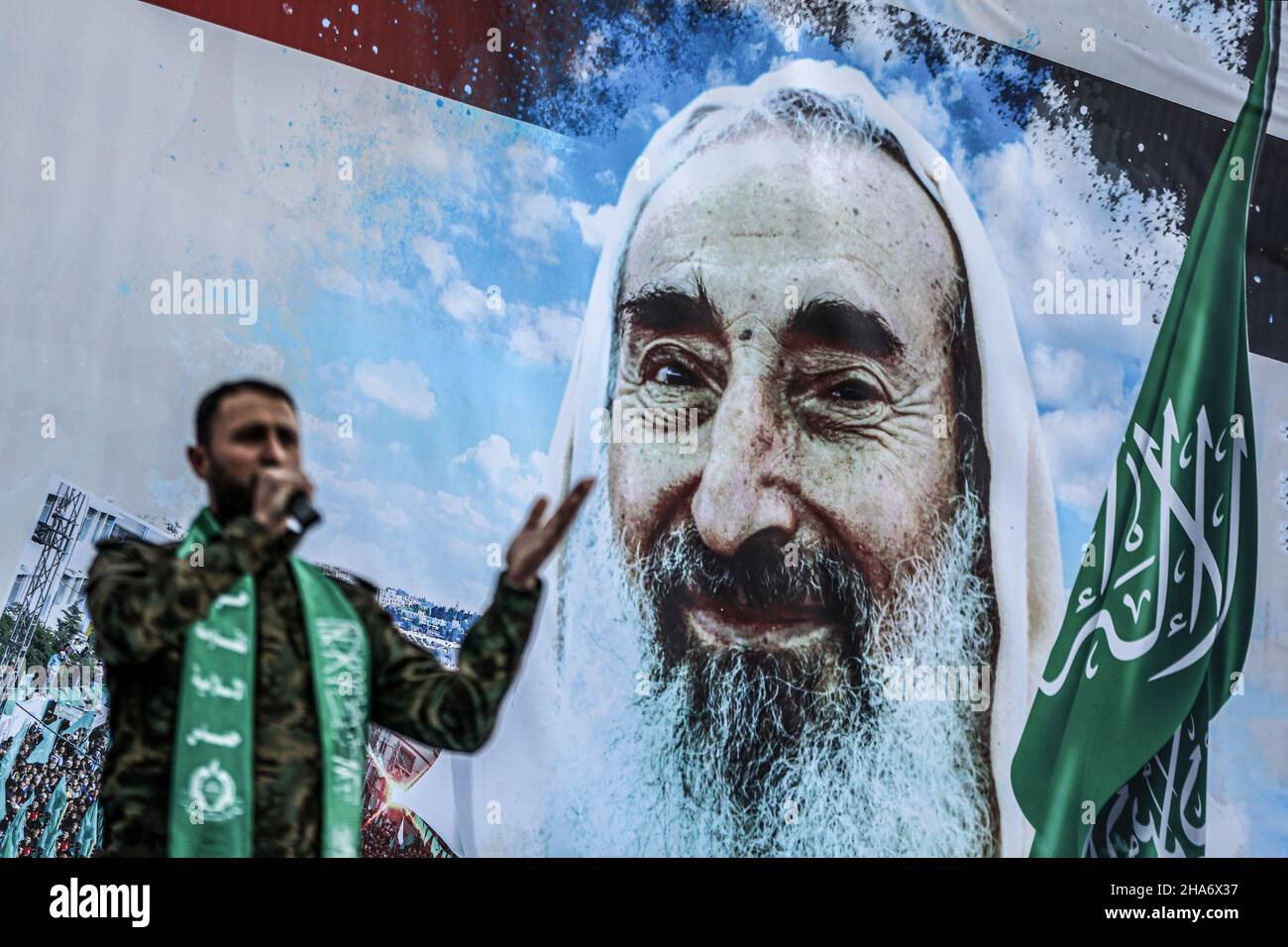 A Palestinian speaks to Hamas supporters with a background of a picture ...