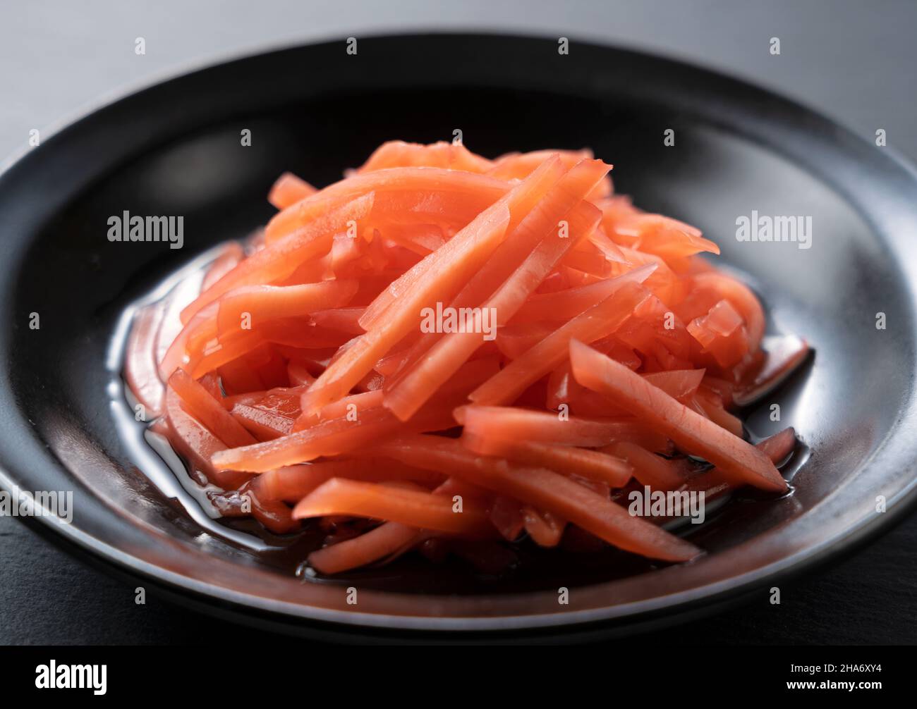 Red pickled ginger placed on a black background. Image of red pickled ...