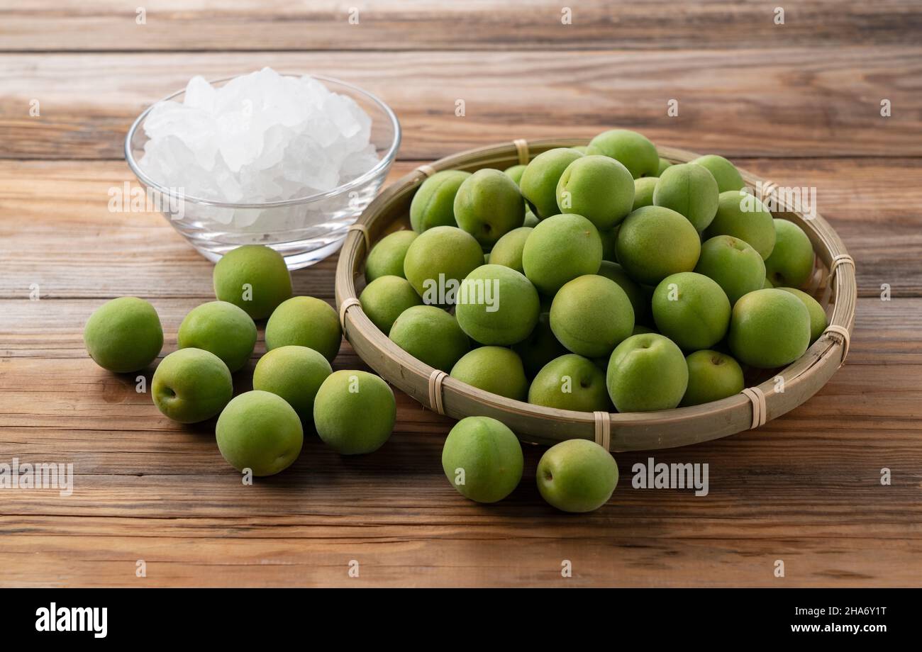 Unripe ume fruit and rock sugar on a wooden background. Preparing to ...