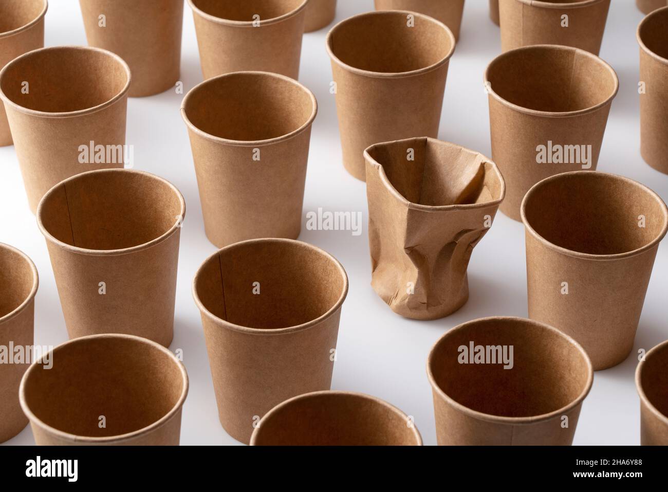 A lot of brown recycled paper cups and one crushed paper cup on a white ...