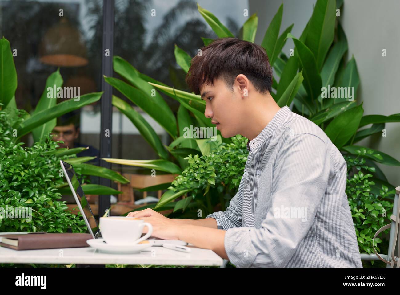 Using advantages of free Wi-Fi. Handsome young man working on laptop ...