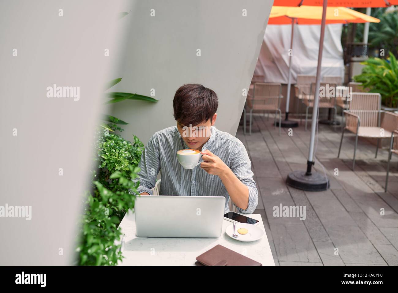 Relaxed man writing in a laptop in a coffee shop Stock Photo - Alamy