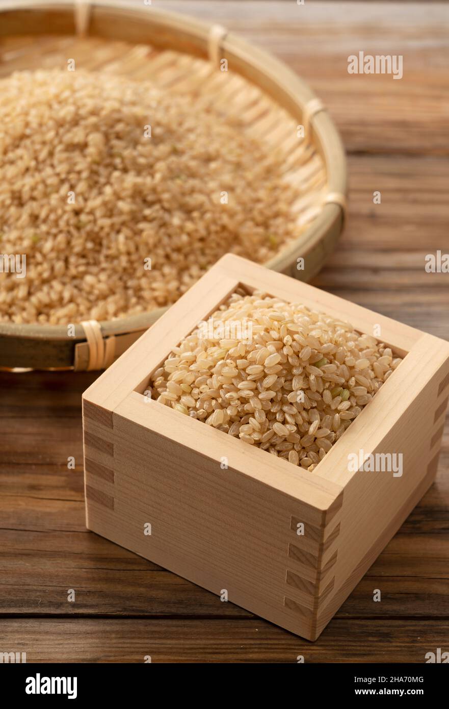 Brown rice in a wooden box and bamboo colander placed on a wooden ...