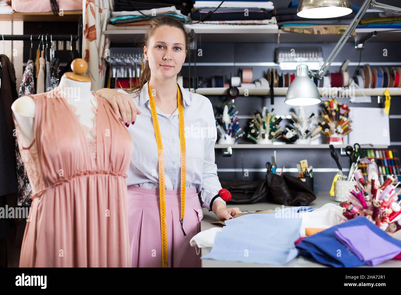 Portrait of female seamstress is who is posing in her design studio in ...