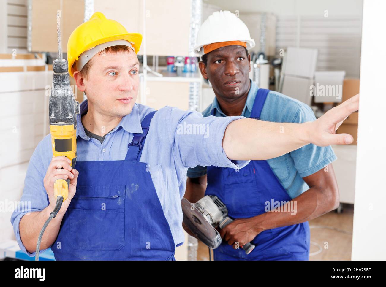 Two male builders working with electric tools at indoors building site ...