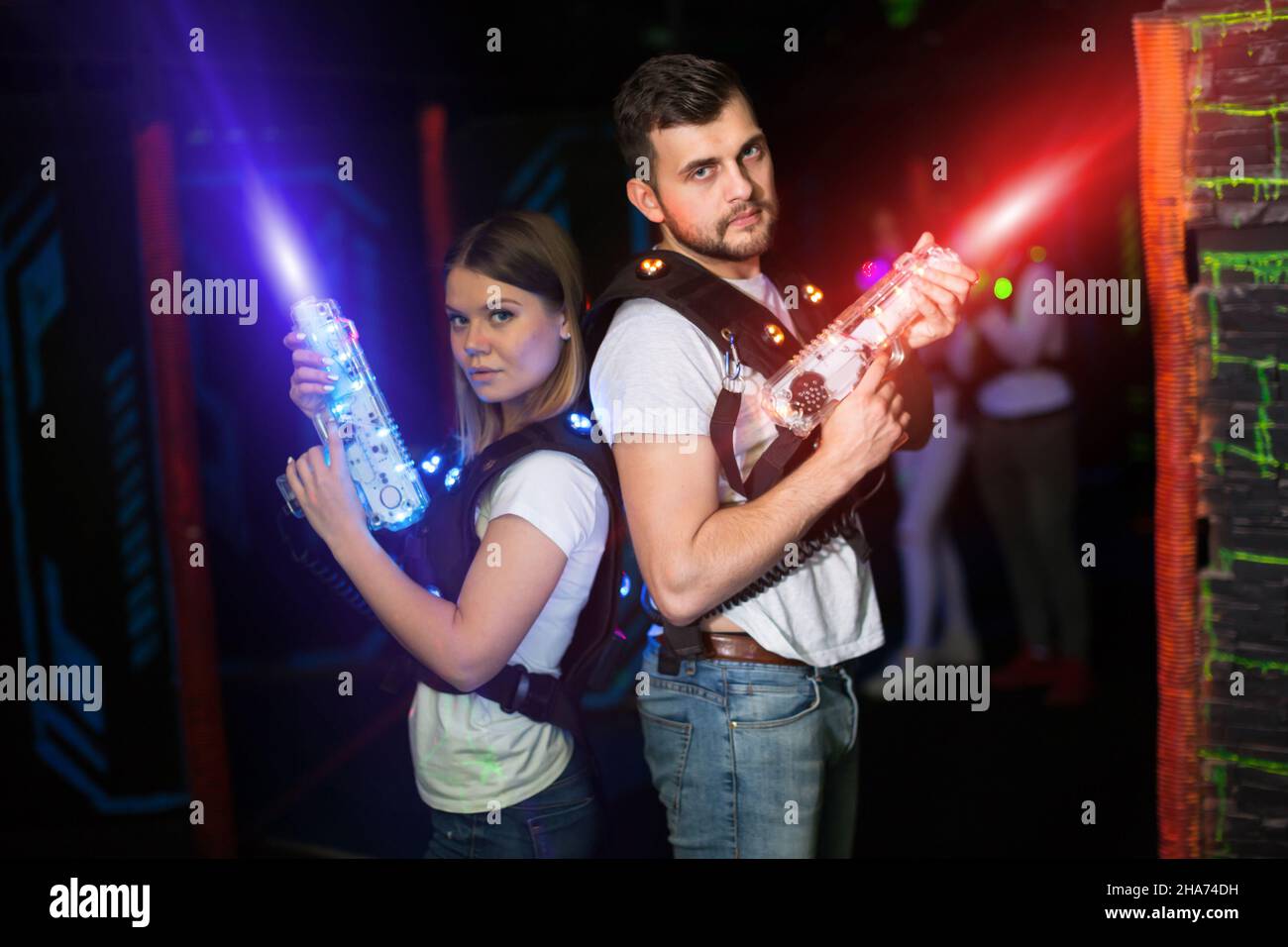 Two confident laser tag players standing back to back with guns on ...