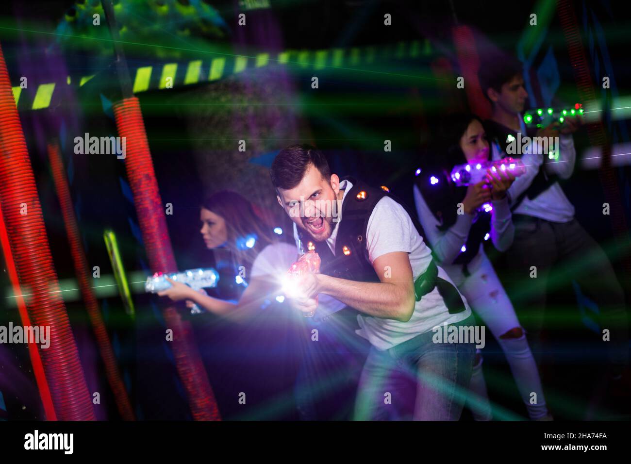 Emotional guy playing laser tag with friends on dark labyrinth in ...