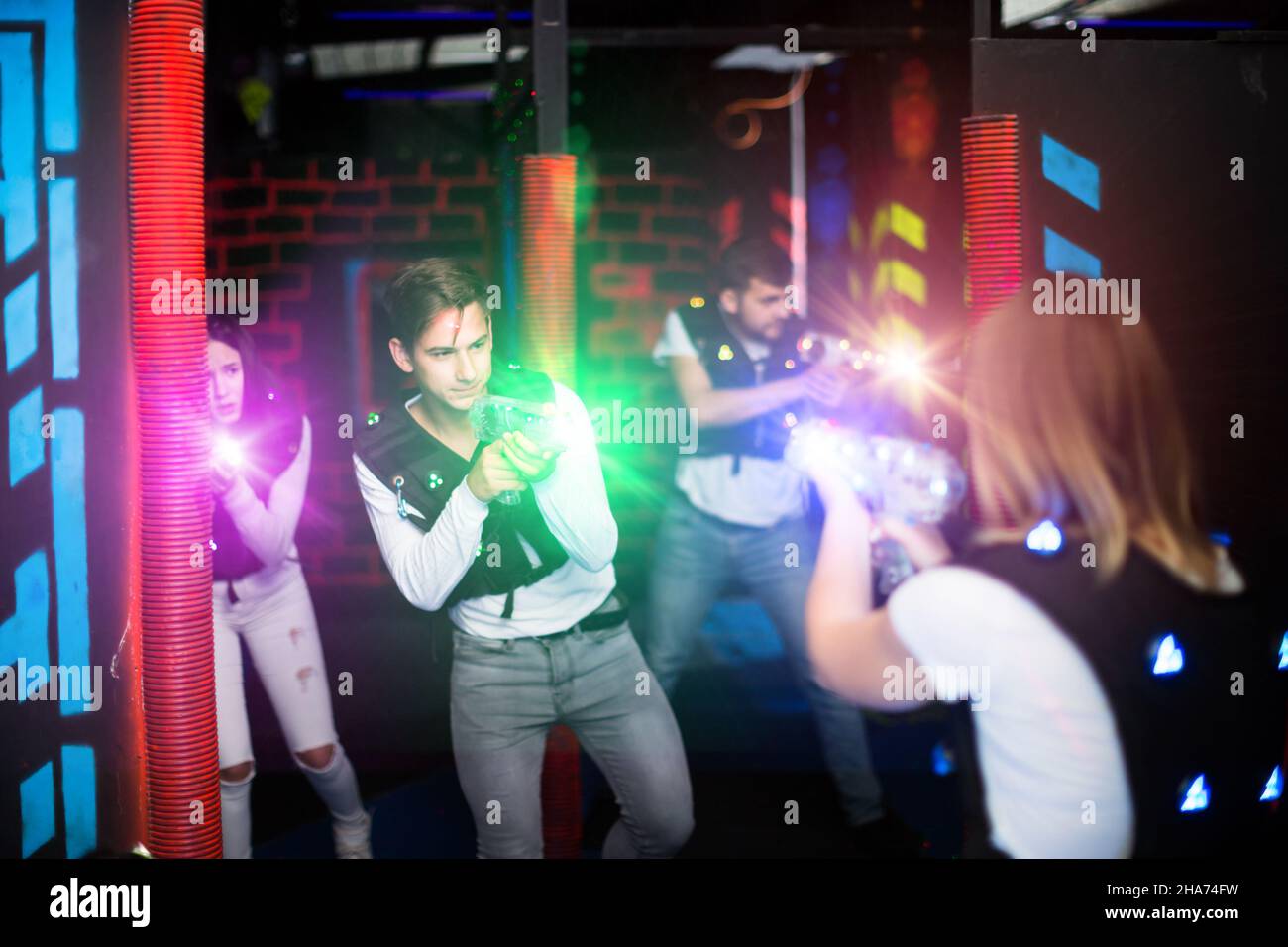 Portrait of guy in colored beams of laser guns during laser tag game on ...