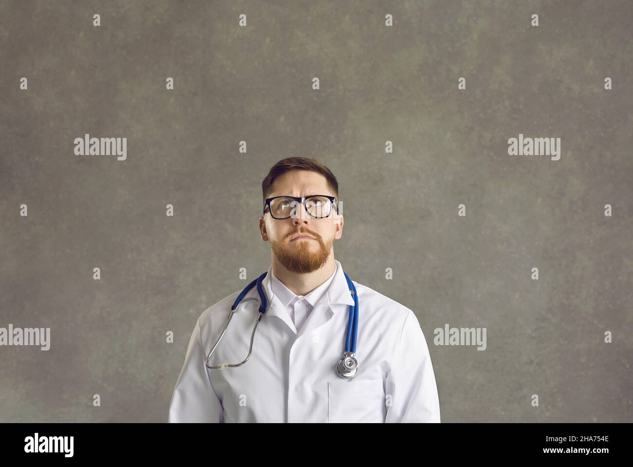 Serious male doctor with a pensive facial expression looking up on a ...