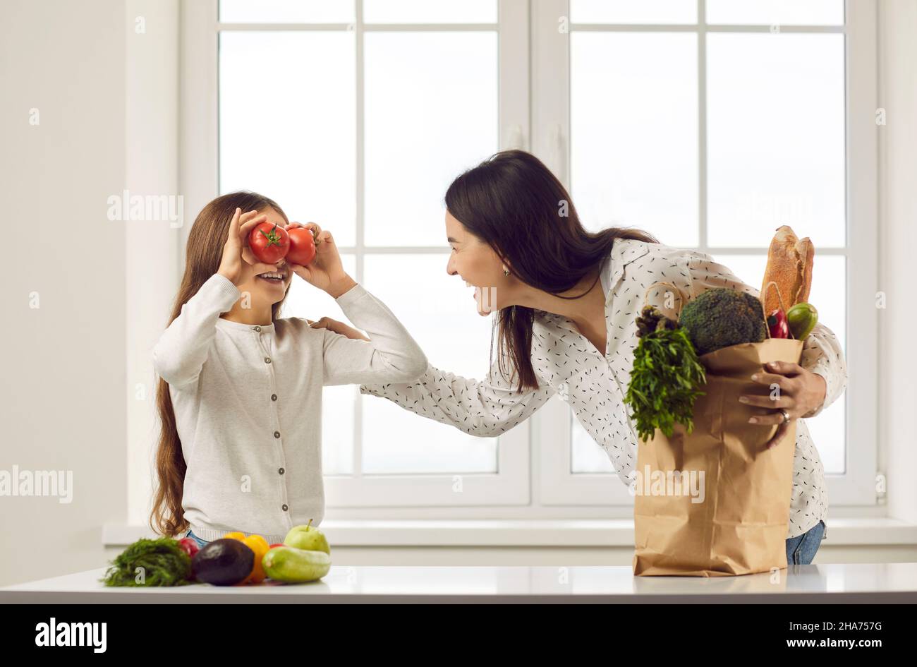 Happy family having fun with vegetables while unpacking healthy foods ...