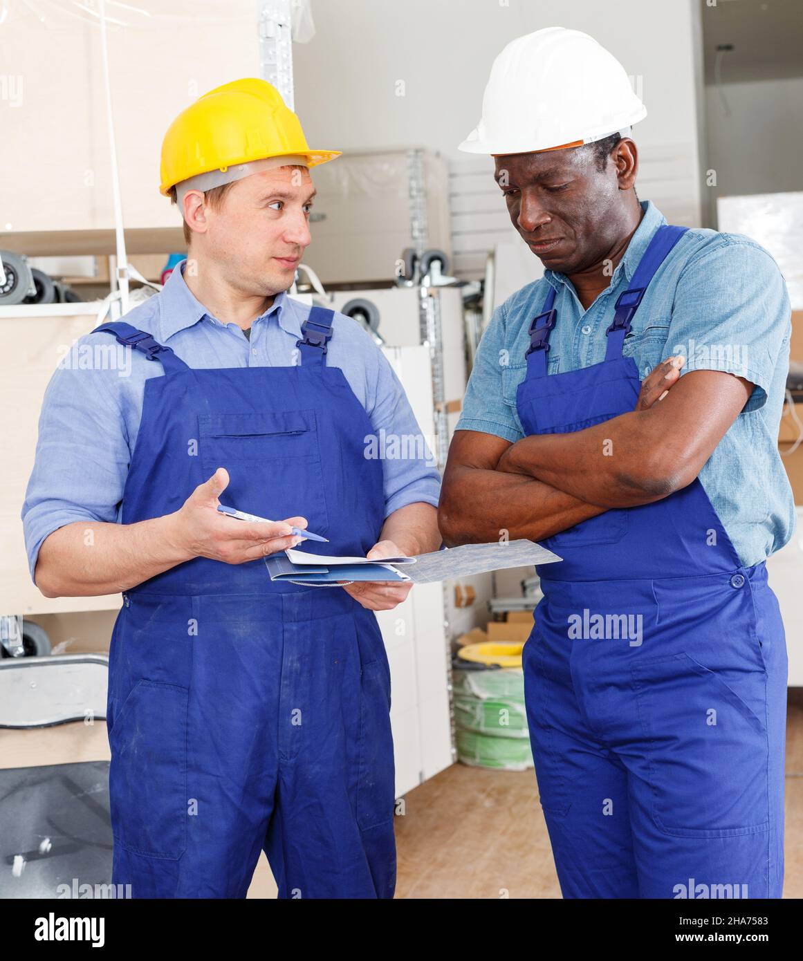 Focused construction workers discussing while inspecting room and ...
