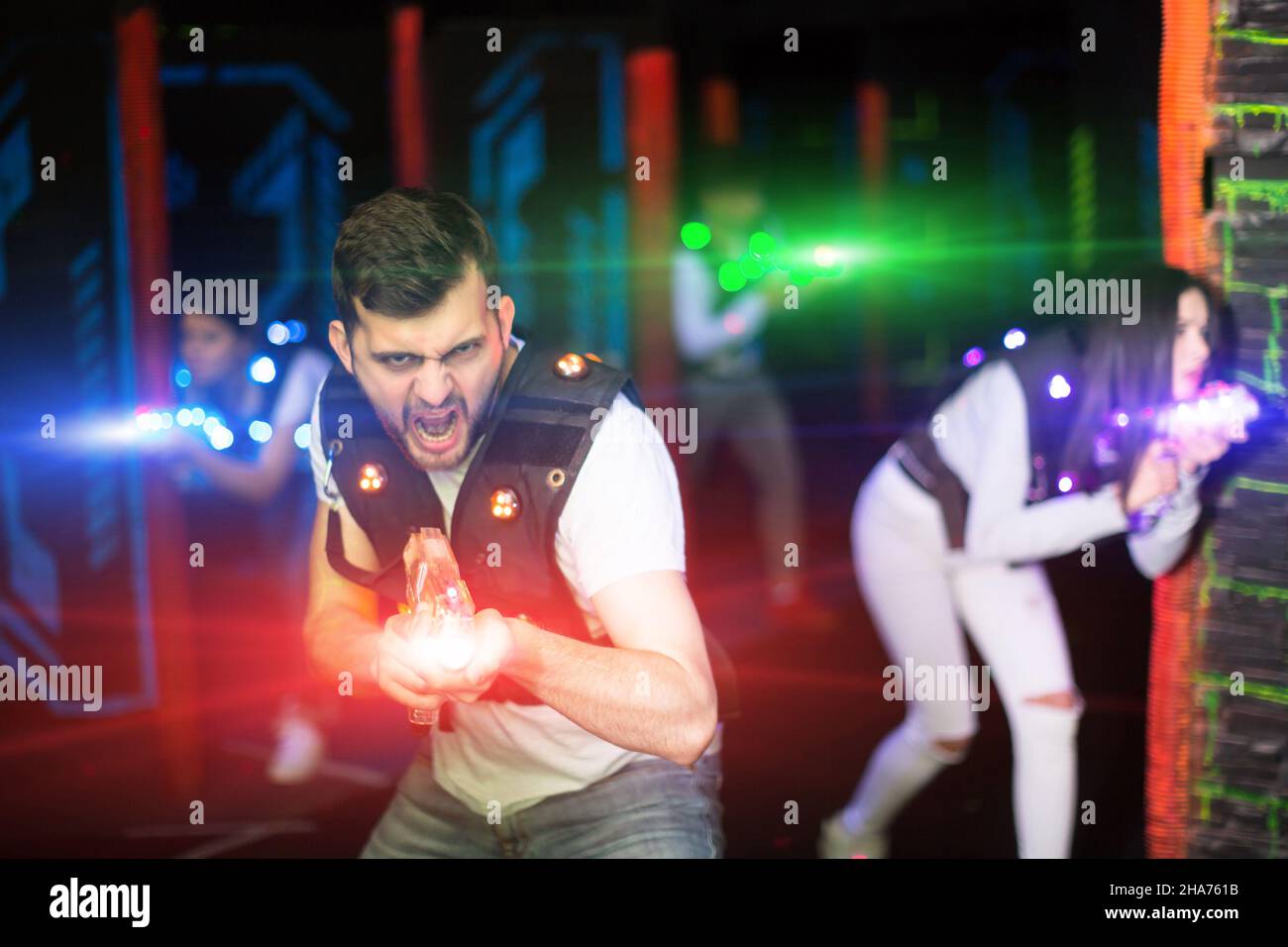 Portrait of guy in colored beams of laser guns during laser tag game on ...