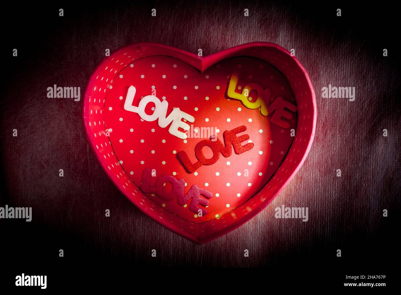 Heart-shaped gift box and four text "LOVE" in box on dark background ...