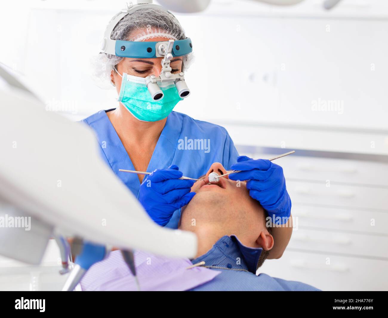 positive adult dentist checking teeth of patient male sitting in ...