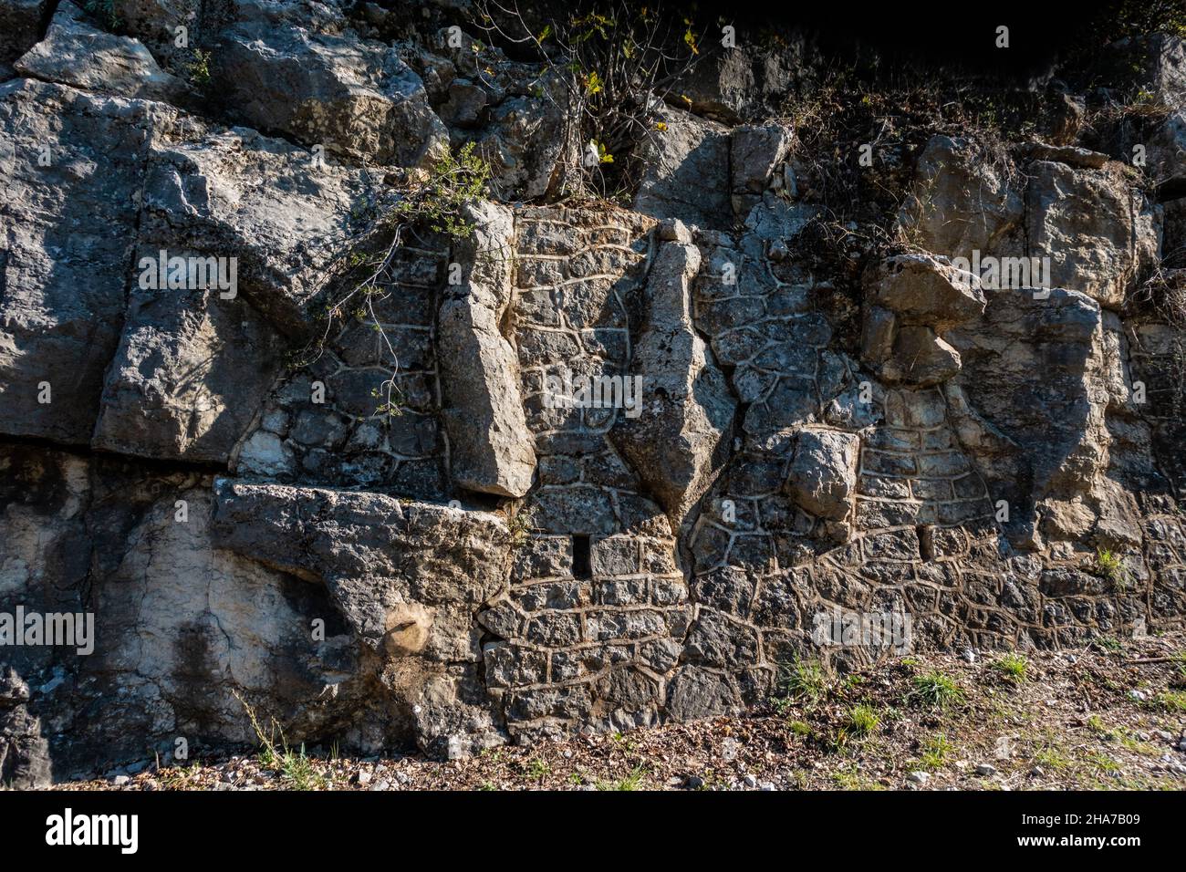 man-made stone wall built into cliff rock face Stock Photo - Alamy