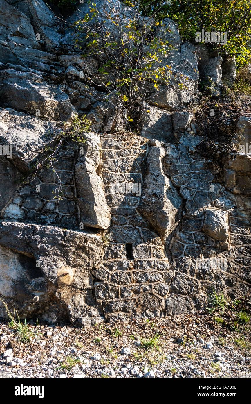 man-made stone wall built into cliff rock face Stock Photo - Alamy