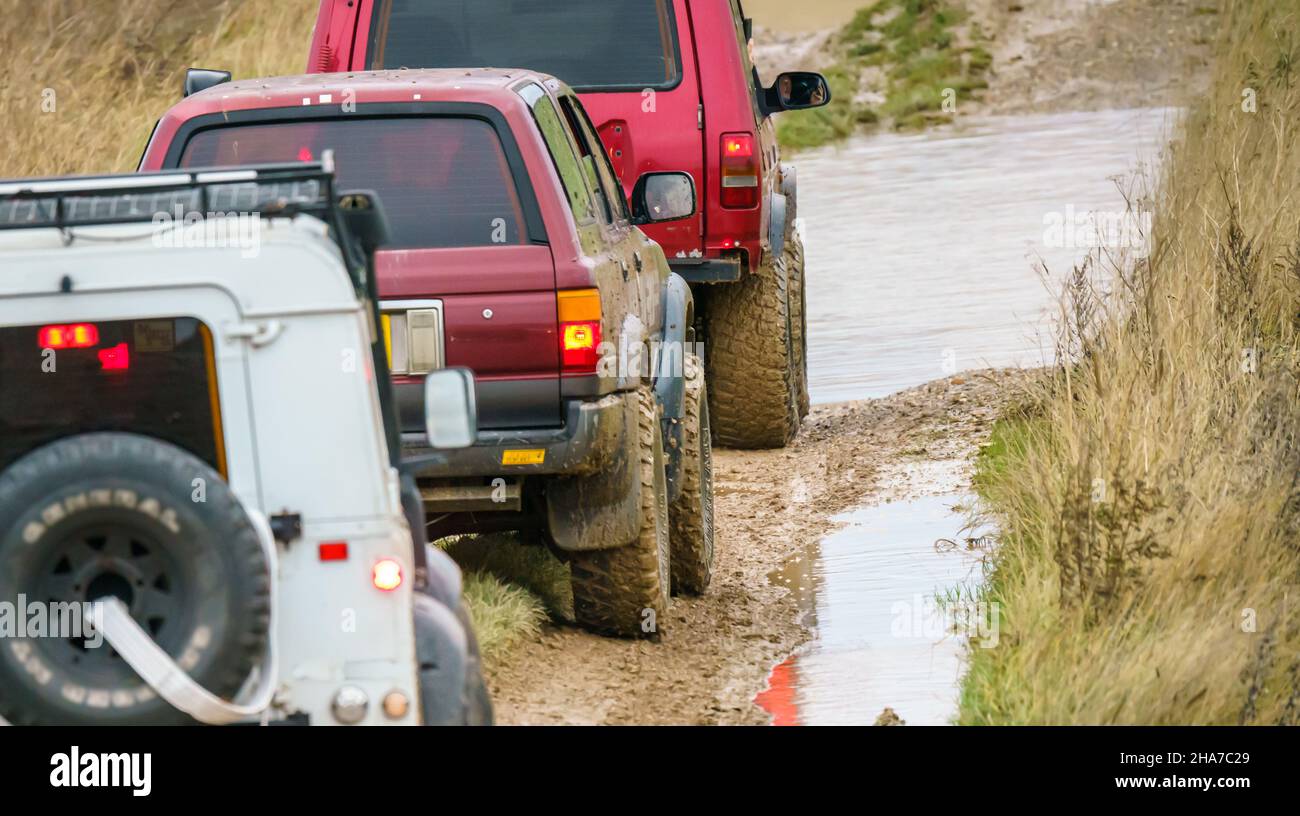 4x4 off-road vehicles driving across mud and water-logged terrain ...