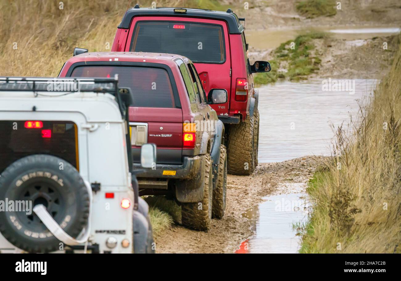 4x4 off-road vehicles driving across mud and water-logged terrain ...