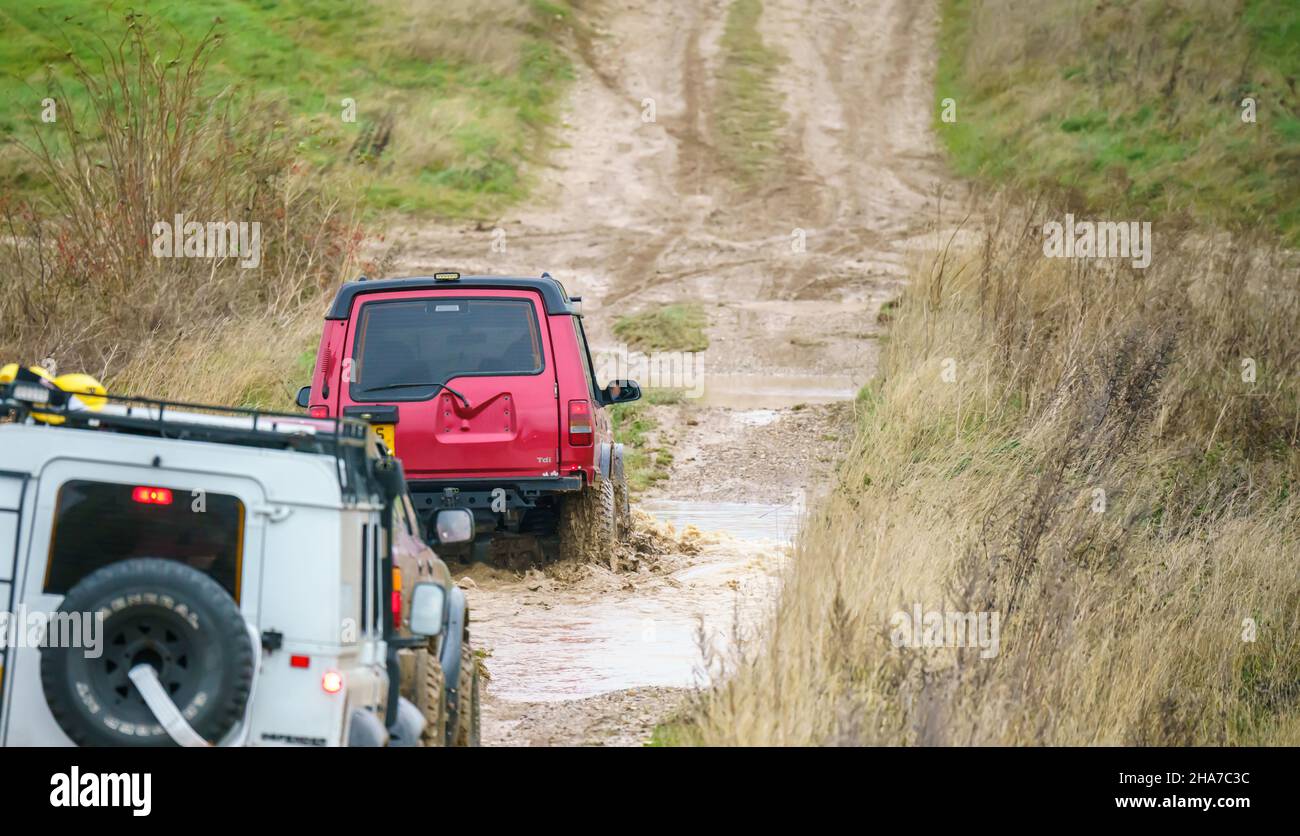 4x4 off-road vehicles driving across mud and water-logged terrain ...