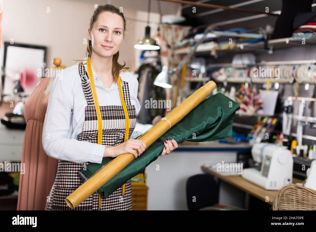 Serious female professional sewer holding tubes with material at sewing ...