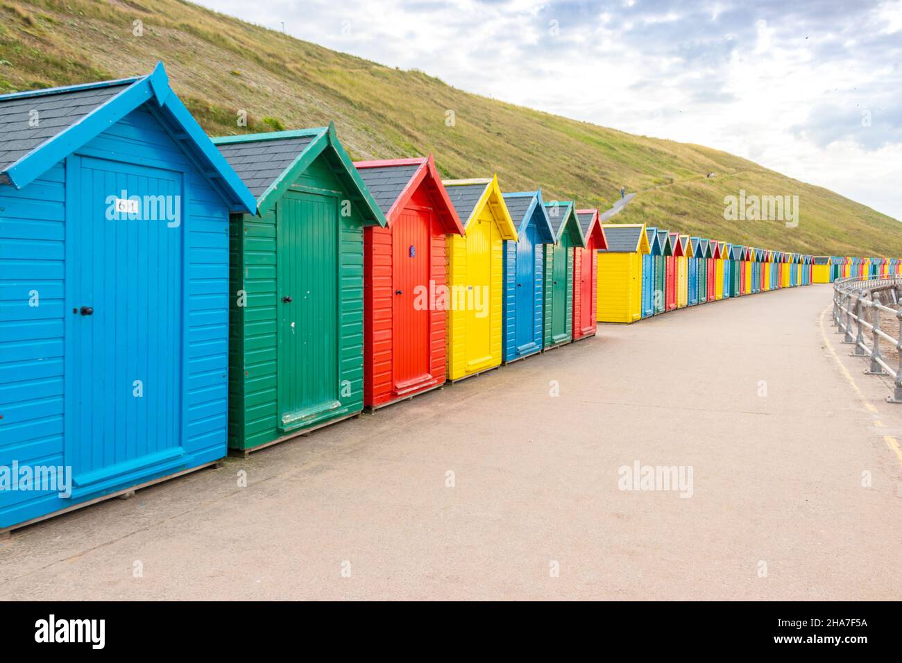 colourful row or line of beach huts chalets on the seafront promenade ...