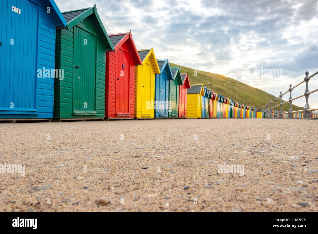colourful row or line of beach huts chalets on the seafront promenade ...
