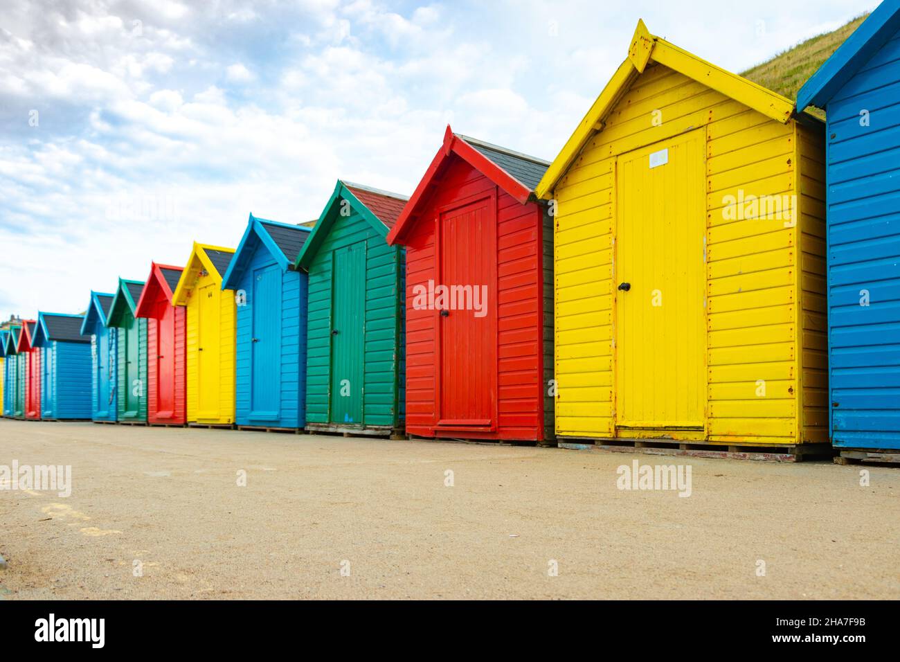 colourful row or line of beach huts chalets on the seafront promenade ...