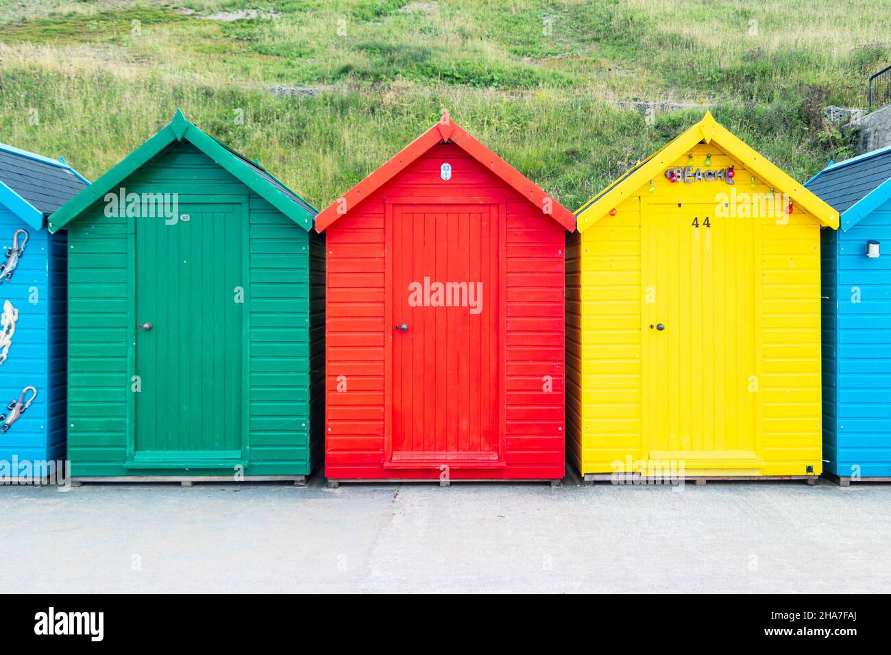 colourful row or line of beach huts chalets on the seafront promenade ...