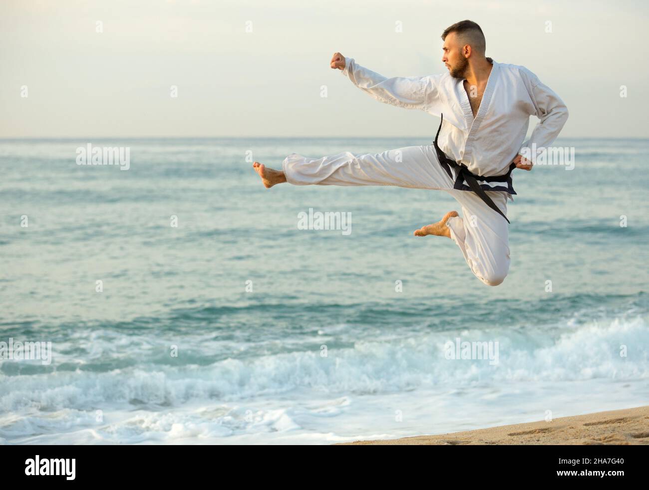 Adult man is training kick in jump on the beach near the sea Stock ...