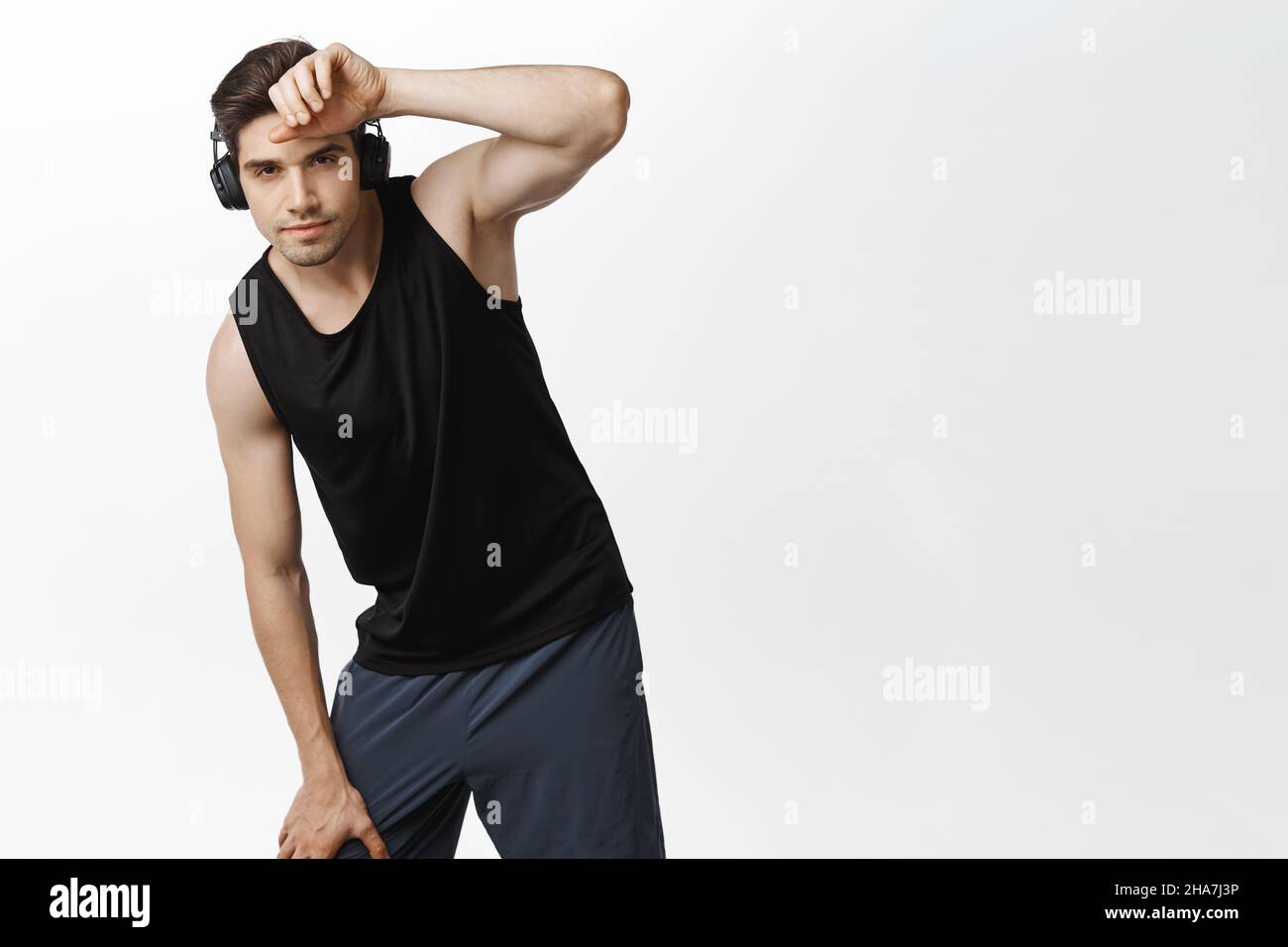 Image of healthy man workout and listen music in headphones, wipe sweat ...